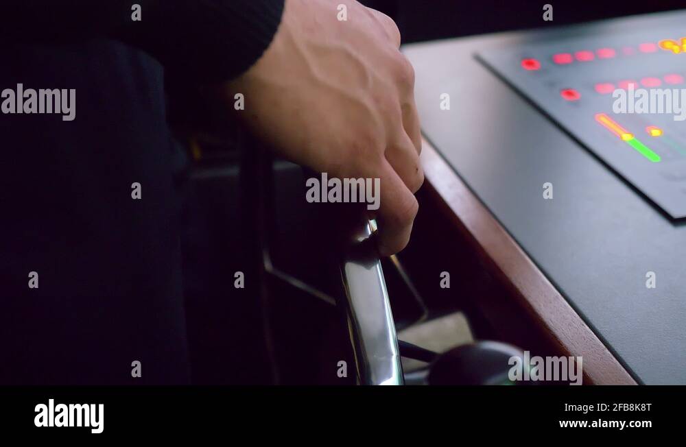 Close of a merchant marine students hands steering in a ship simulator ...