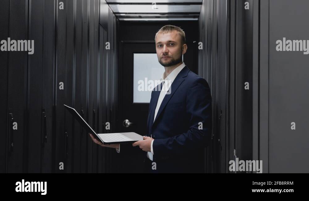 IT engineer face portrait with laptop in server room of datacenter ...
