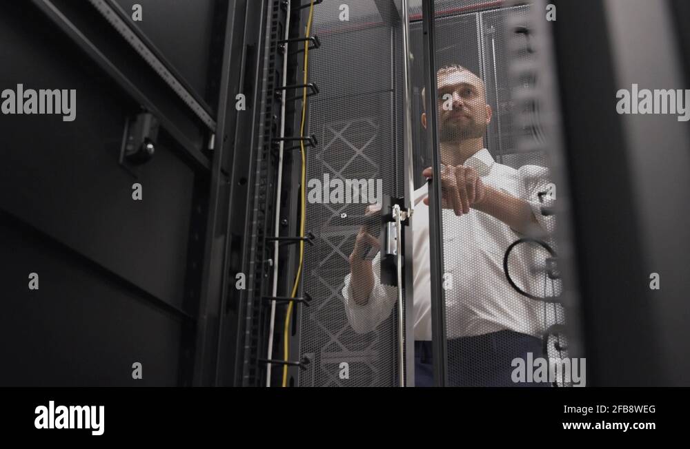 Man opening server rack of hosting system in big data center Stock ...