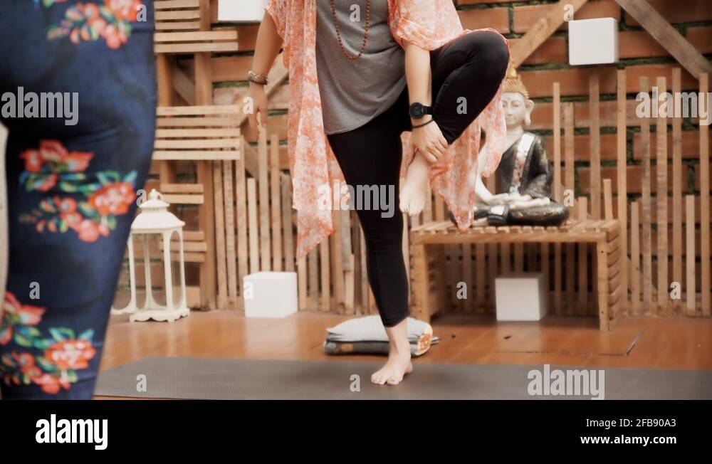 A yoga teacher in a classroom, showing her student the right posture ...