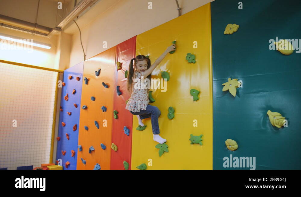 Little girl jumping into the pool with colourful soft cubes in a ...