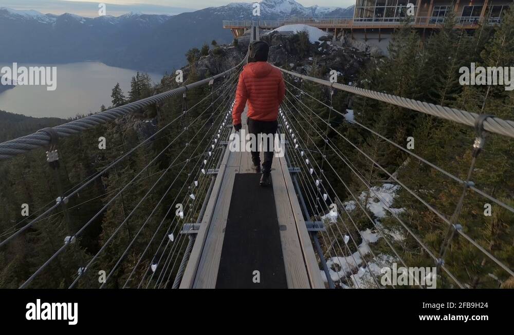 man walking across suspension bridge in the mountains, 60 fps good ...