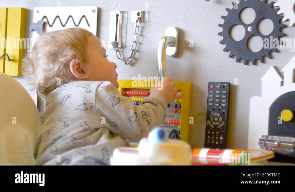 Busy-board for children. Cute baby boy playing with busy board on the ...
