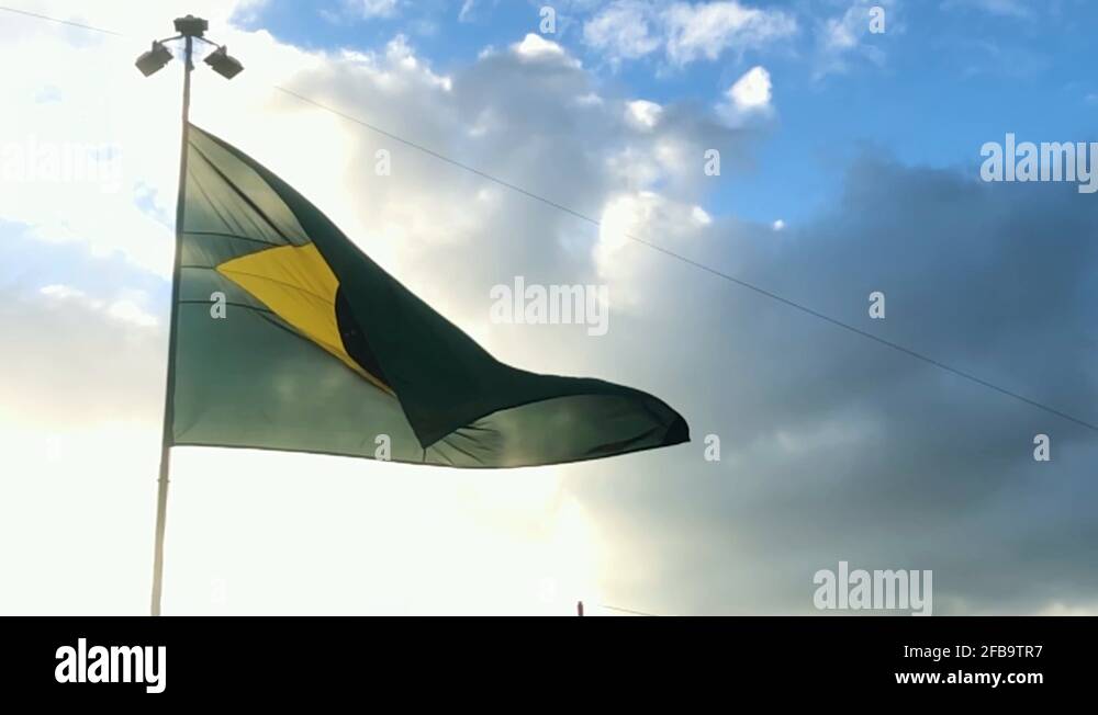 Brazil flag flying in slow motion with bright cloudy sky background ...
