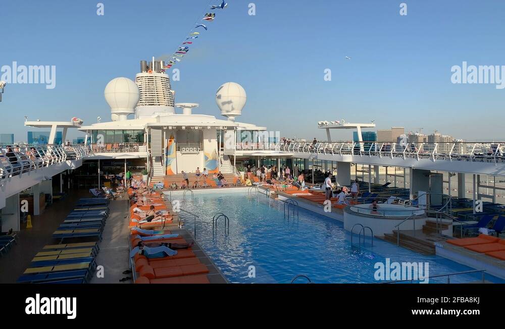 Passengers aboard a cruise ship enjoying the sun and a swim in the pool ...