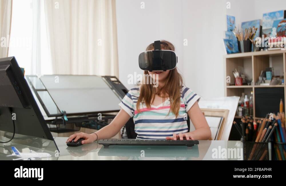 Teenage girl using a mouse a keyboard and a vr headset to play a game ...