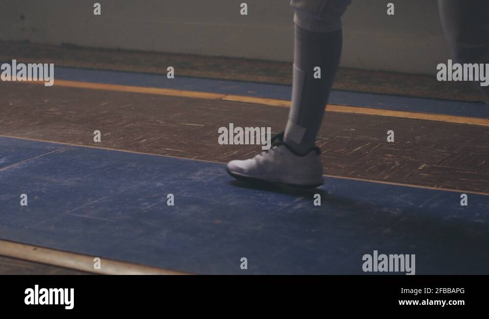 Female fencer training on a strip in a dark and dusty fencing gym Stock ...