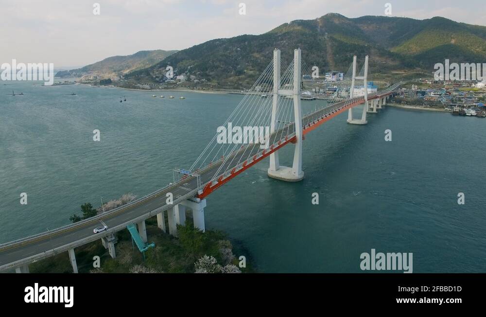 A car passing through the Sacheon Bridge, a sea cable car behind it ...