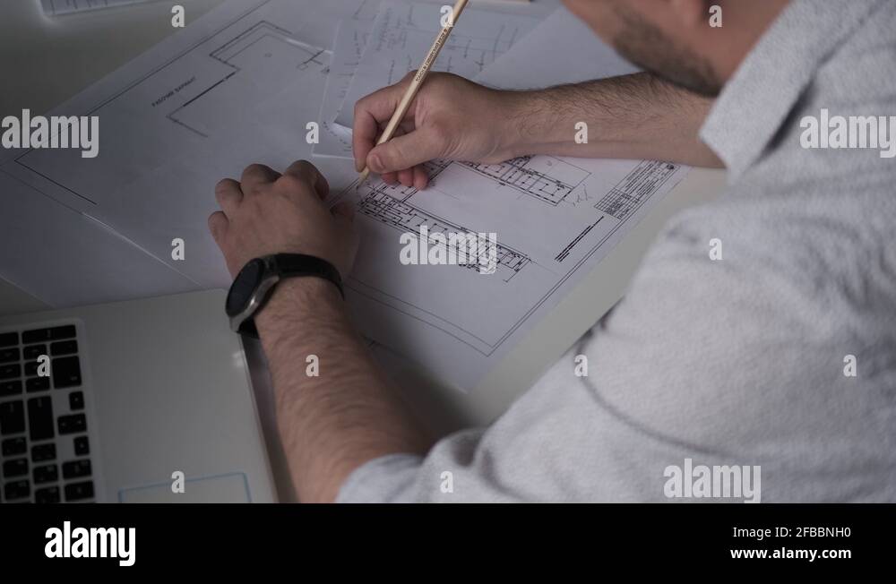 Architect works with blueprints and documents at his desk. back view ...