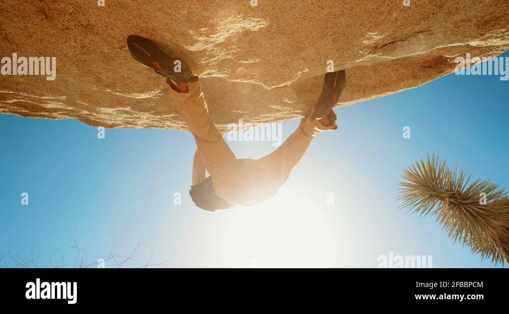 Low extreme angle of young man rock climbing reaching for hold with ...