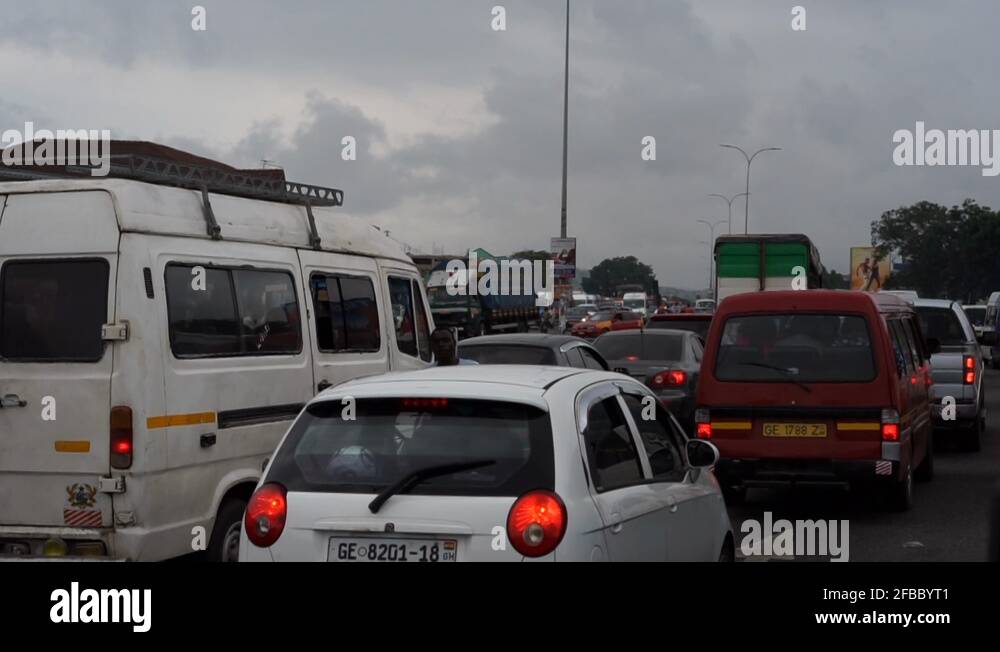 Scenery of traffic Accra, Ghana. A woman is crossing the street with ...