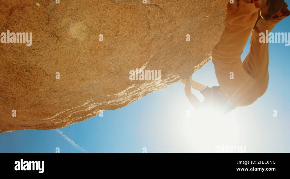 Low extreme angle of young man rock climbing reaching for hold with ...