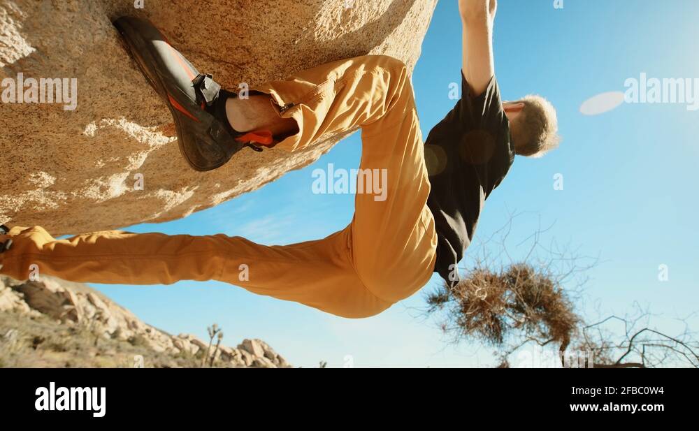 Low extreme angle of young man rock climbing reaching for hold with ...