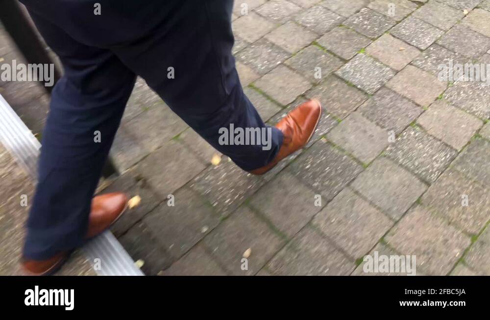 SLOW MOTION: Man walking down some stairs on a paved surface Stock ...