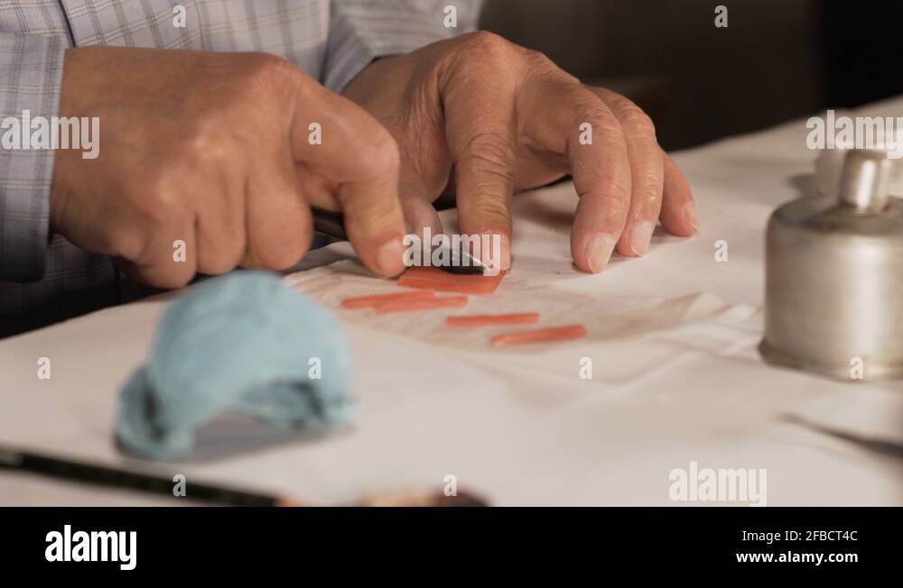 Dentist cutting/preparing modelling wax in strips for a denture cast ...