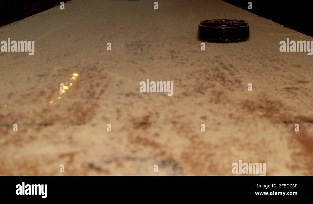 Slow motion puck puck sliding down a shuffleboard table from a player ...