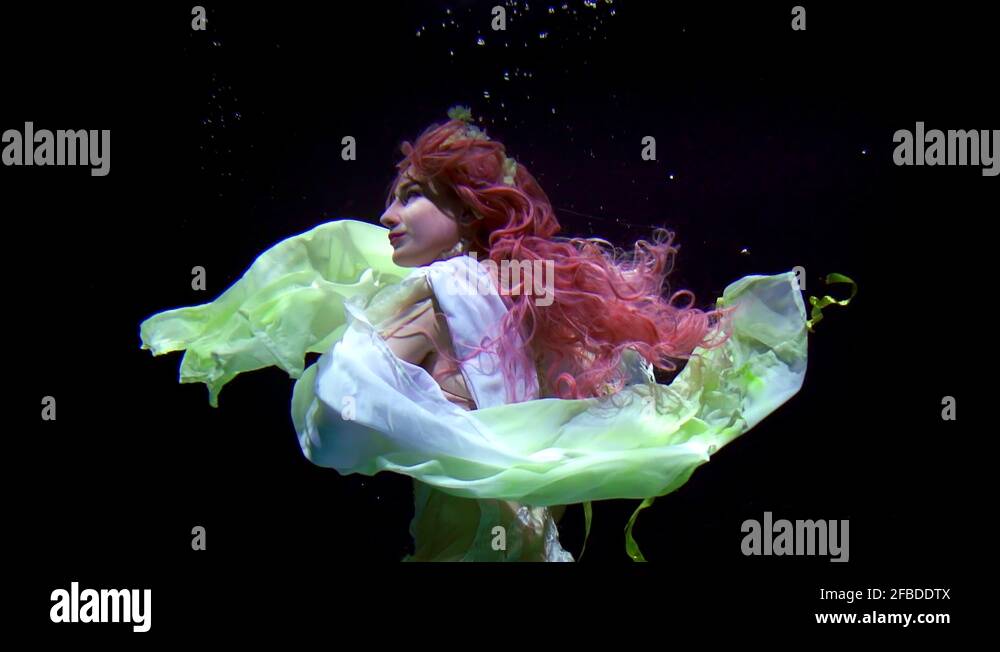 fairytale princess is floating underwater in darkness, spinning and ...