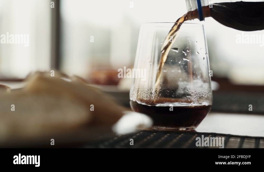Static shot of soda (cola) being poured inside of a glass cup on a ...