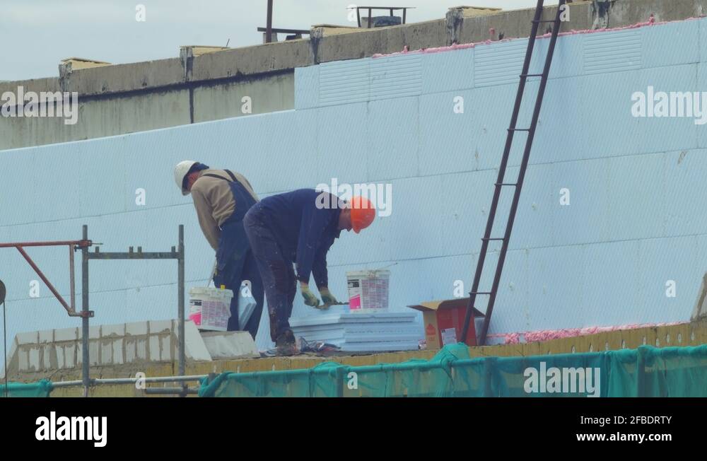 Builders sticking polyfoam thermal insulation plates on the exterior ...