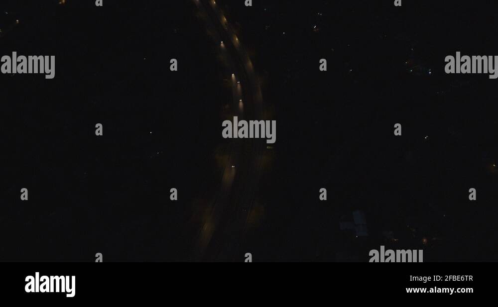 Aerial helicopter night flyover of a city lights twinkling, tilt up to ...