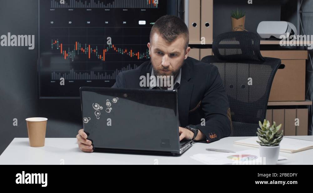 Young man in a modern office works at the computer, hits the screen and ...