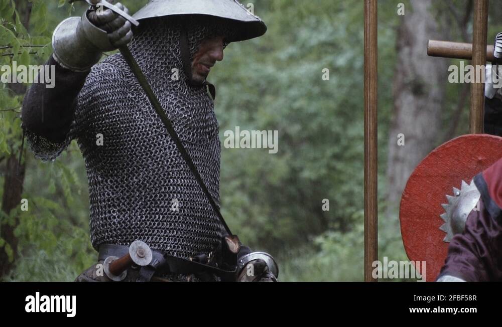 Medieval soldier in chainmail armor is putting his sword in the sheath ...