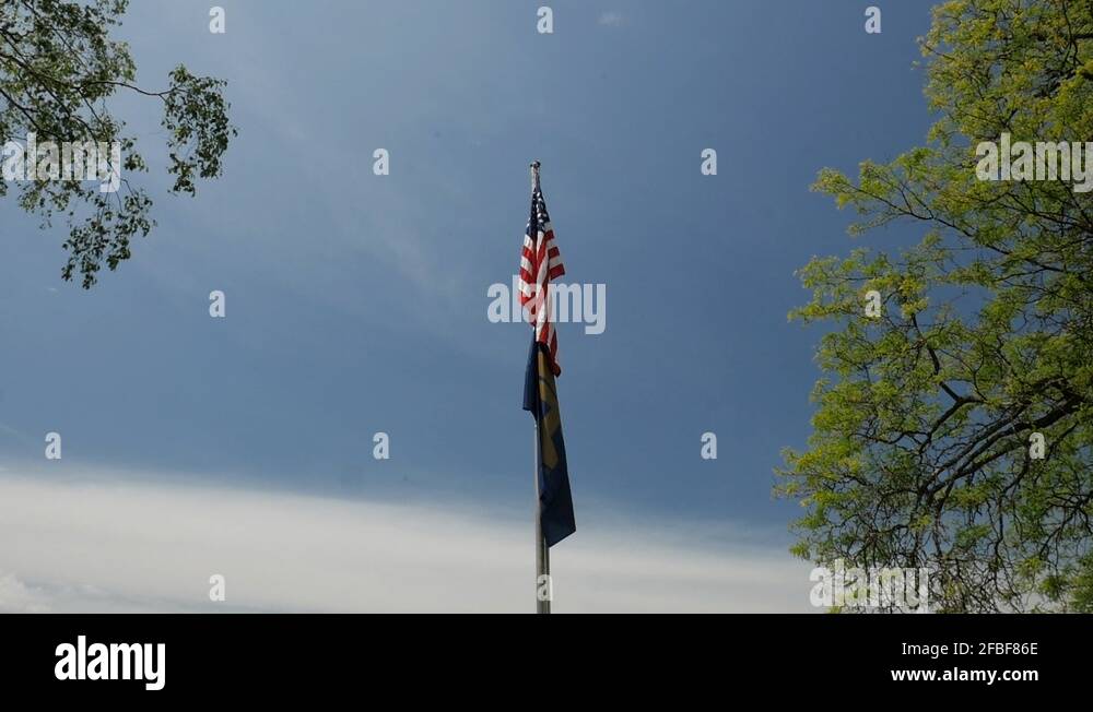 American and Notre Dame flag sitting still on a flag pole with dark ...