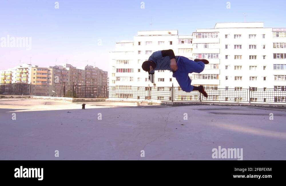 Man wearing a mask runs across the roof of a tall building jumping ...