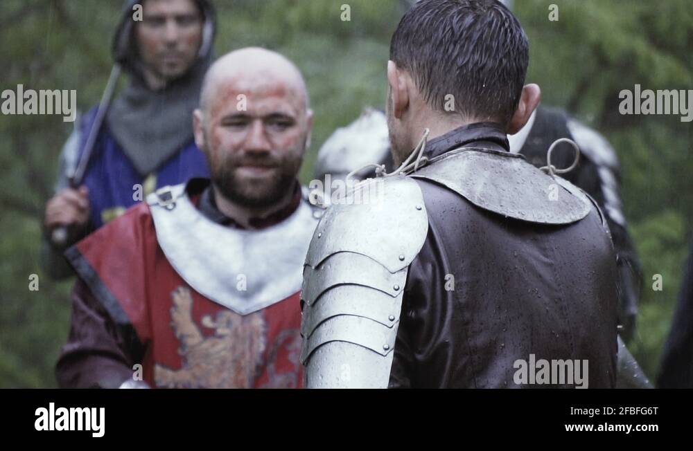 Two knights in metal armor are talking to each other under the rain ...