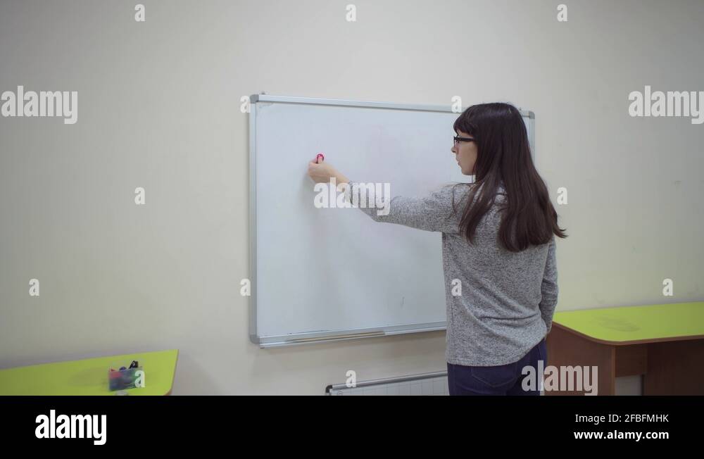 Teacher stands at whiteboard and explains rules of addition in ...