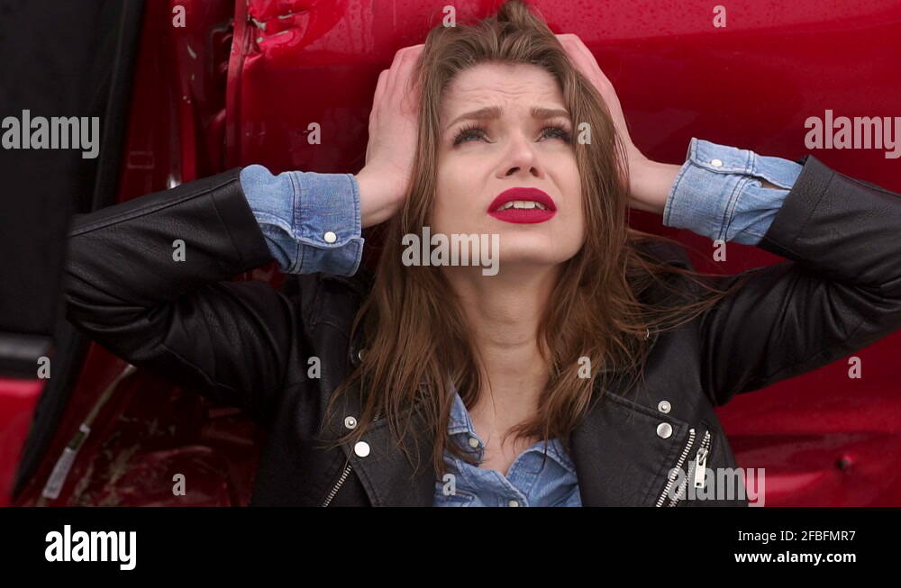 A girl crying sitting on the ground near a broken car, she was in an ...
