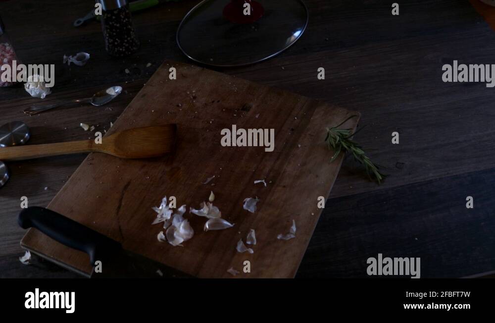 A pan of a messy table after meal prep with utensils, dark and moody ...