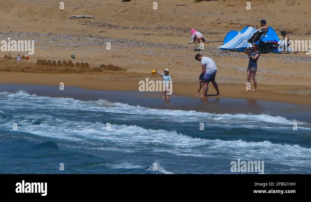 family with children playing on the beach in a windy and sunny day ...