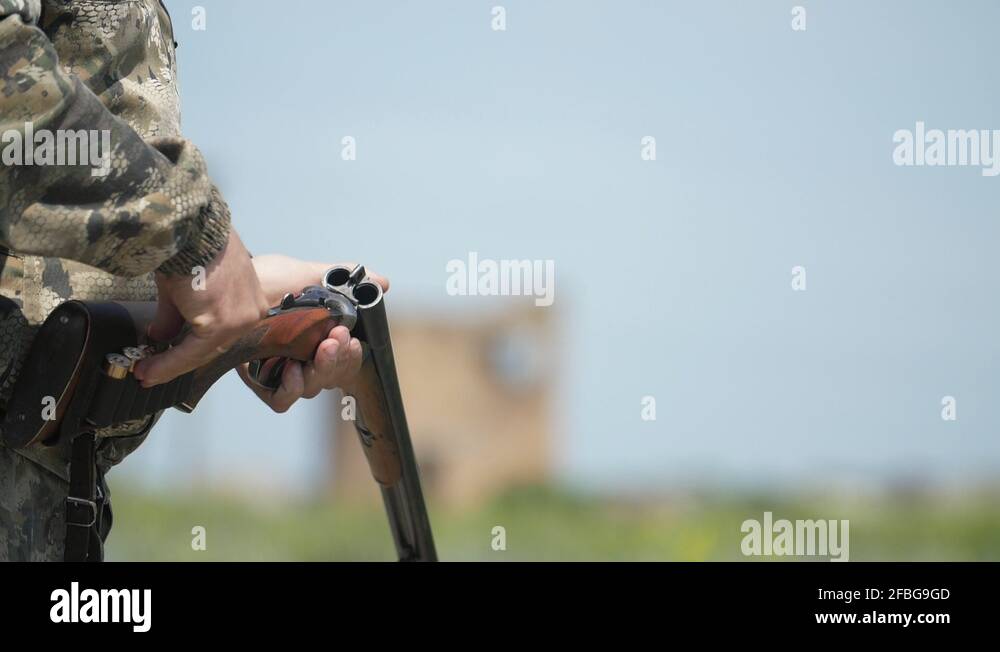 Military man loading his double-barrel rifle on a range on a sunny day ...