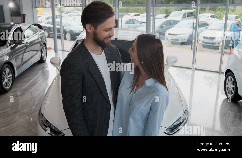 Visiting car dealership. Beautiful couple is holding a key of their new ...
