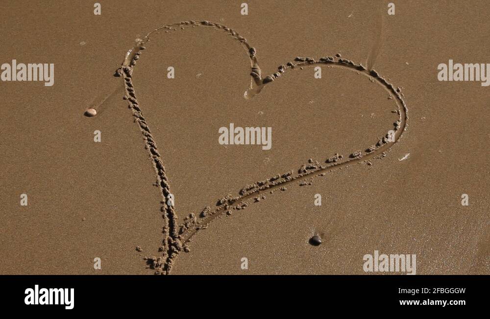 Heart symbol drawing washed away by tide at the beach Stock Video ...