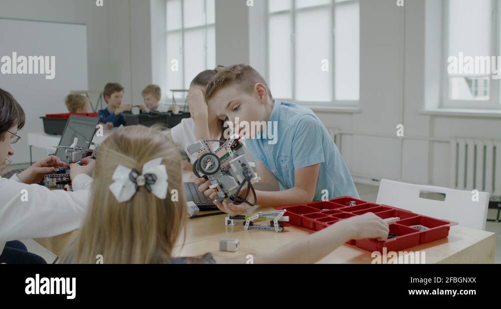 Curious kids working on a programable robot during robotics class at ...
