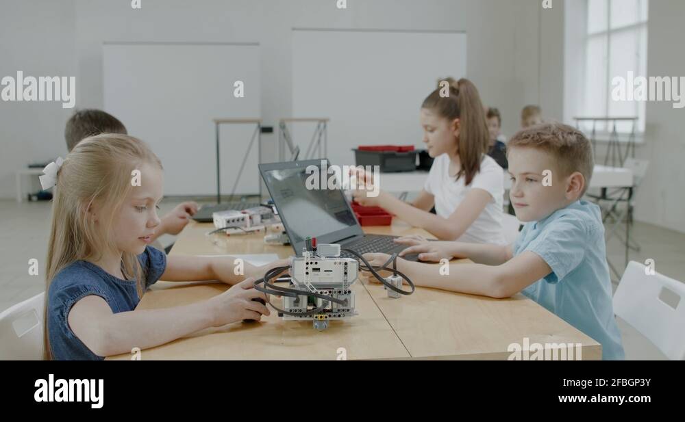 Curious kids working on a programable robot during robotics class at ...