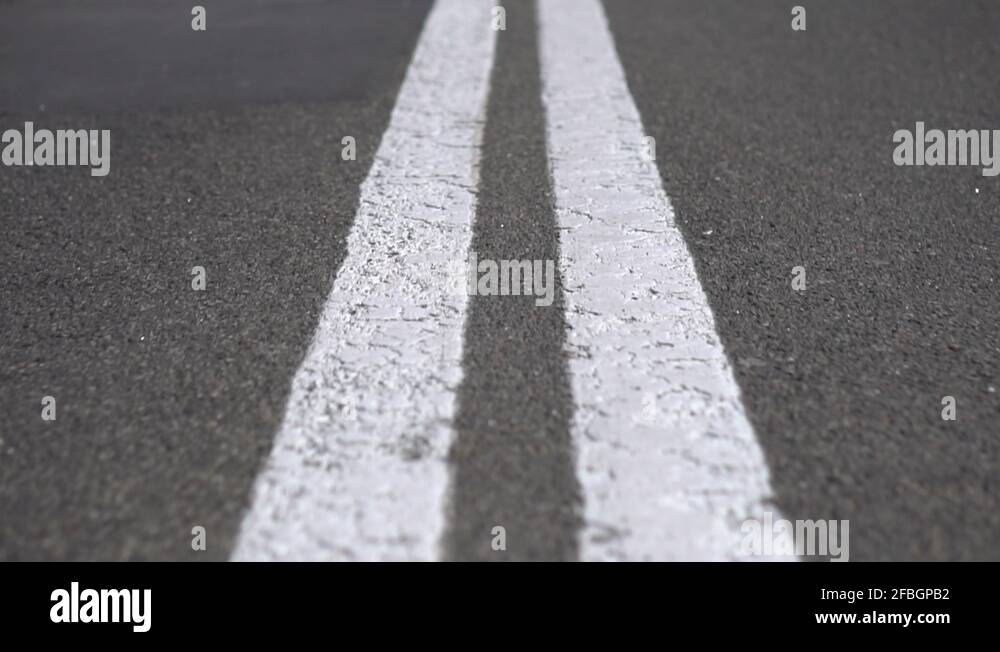 Dividing line on the asphalt road. Close-up. The camera moves along ...