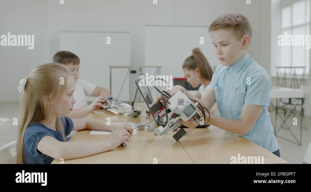 Curious kids working on a programable robot during robotics class at ...