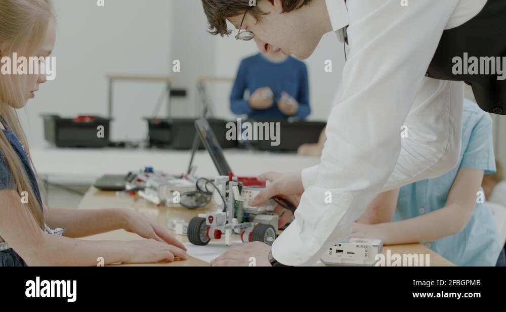 Curious kids working on a programable robot during robotics class at ...