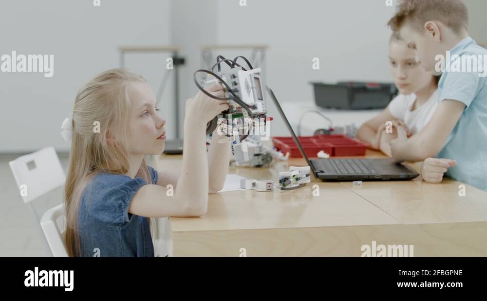 Curious kids working on a programable robot during robotics class at ...