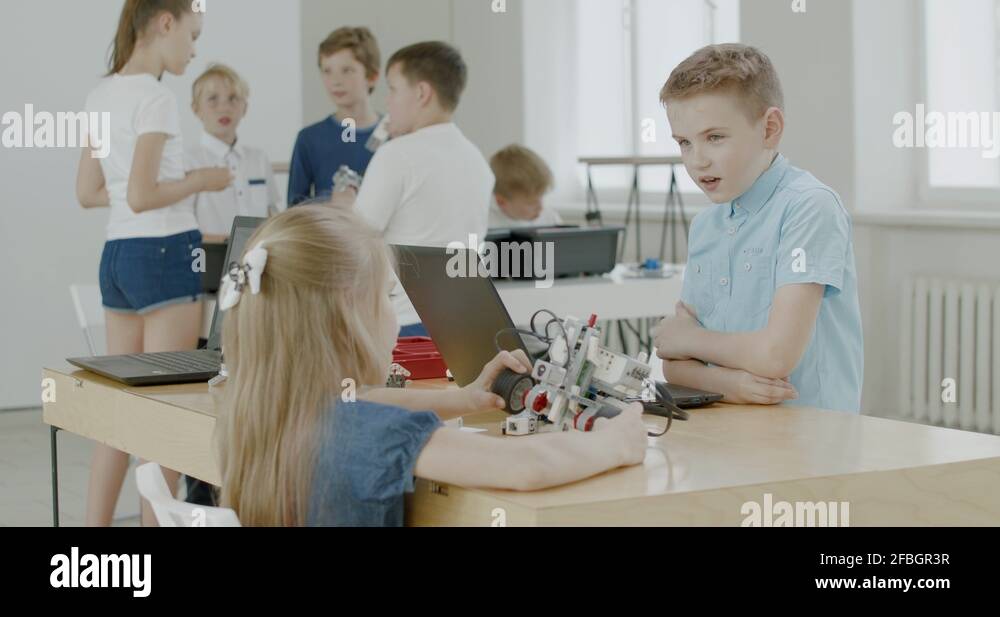 Curious kids working on a programable robot during robotics class at ...