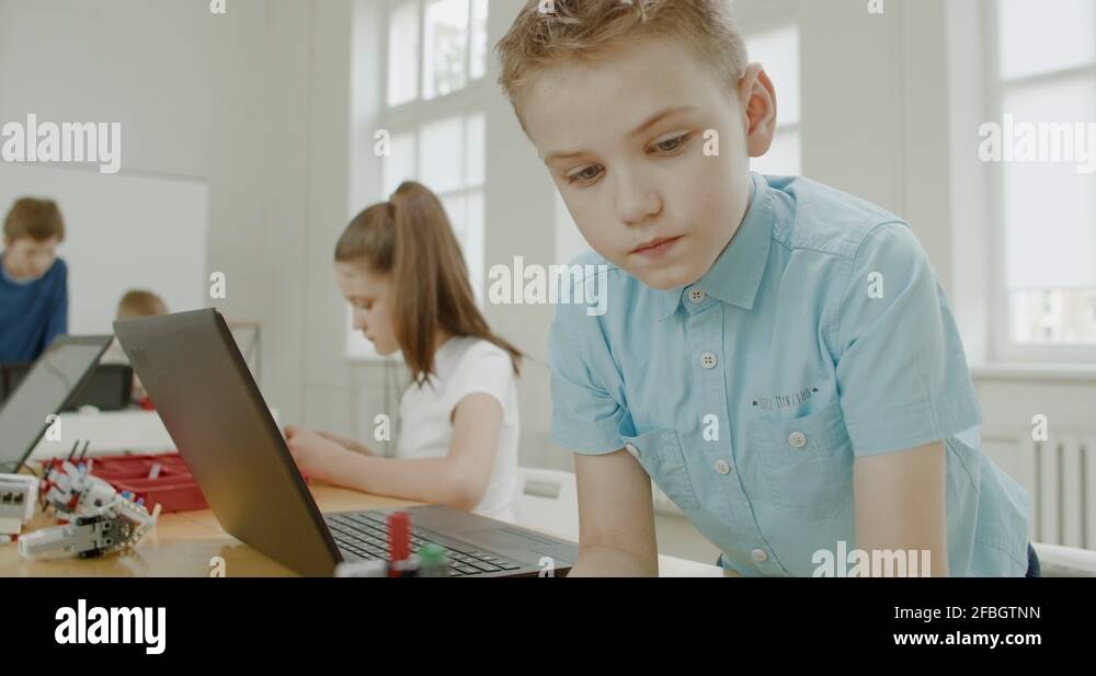 Curious kids working on a programable robot during robotics class at ...