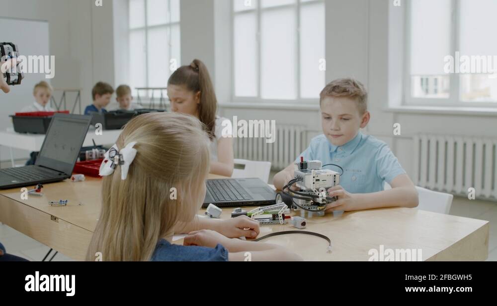 Curious kids working on a programable robot during robotics class at ...