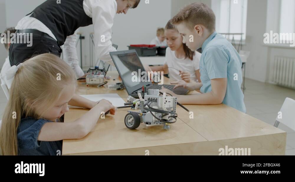 Curious kids working on a programable robot during robotics class at ...
