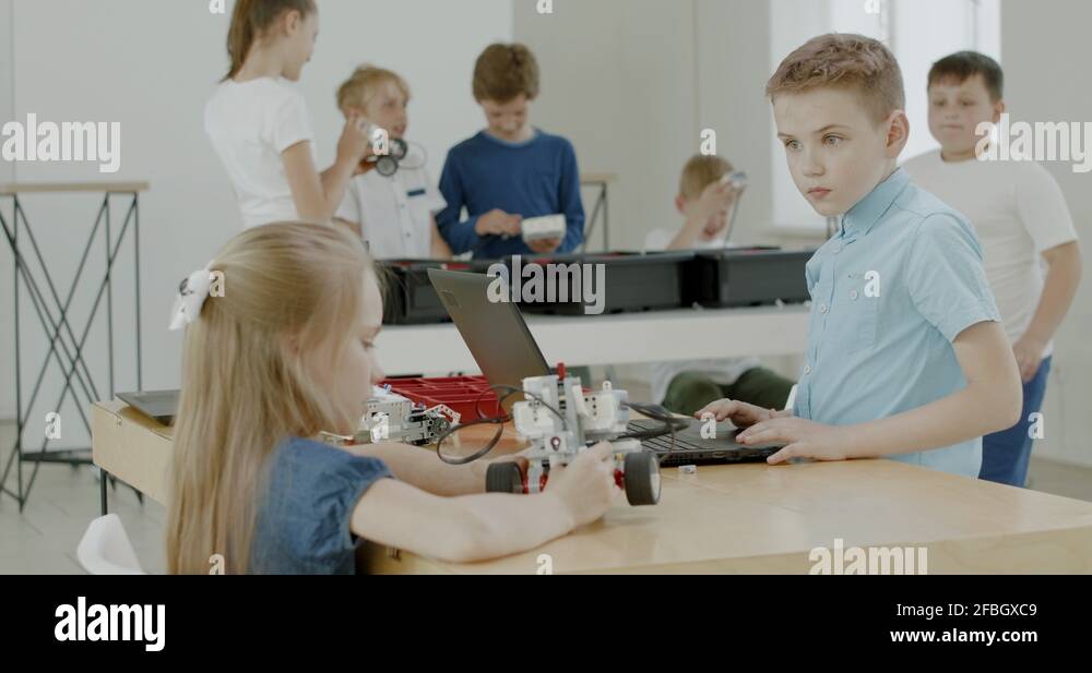 Curious kids working on a programable robot during robotics class at ...