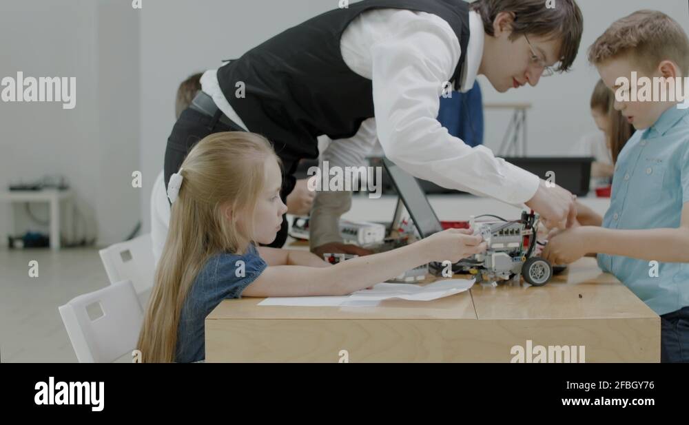 Curious kids working on a programable robot during robotics class at ...