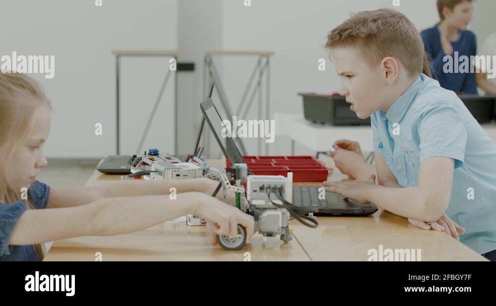 Curious kids working on a programable robot during robotics class at ...