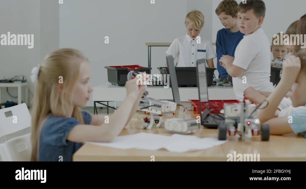 Curious kids working on a programable robot during robotics class at ...